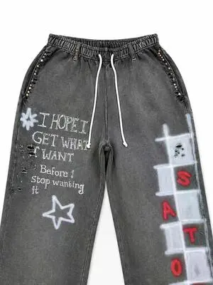 SATOSHI NAKAMOTO Get What I Want Distressed Graffiti-print Trousers