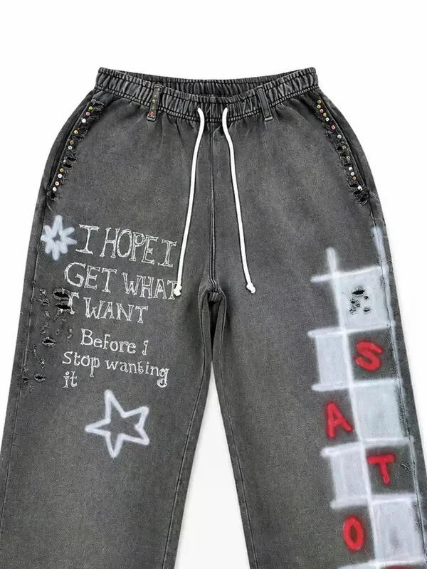 SATOSHI NAKAMOTO Get What I Want Distressed Graffiti-print Trousers