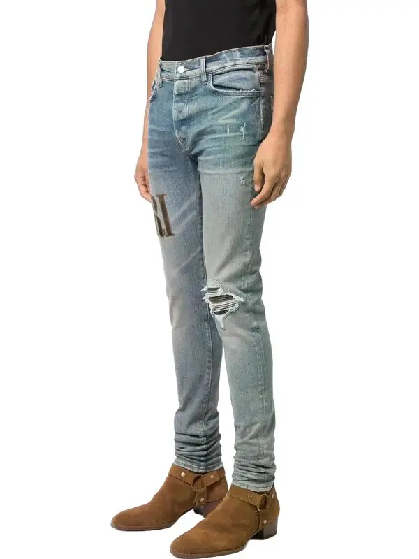 Amiri Logo-embroidered Ripped-detail Slim Cut Jeans - Blue