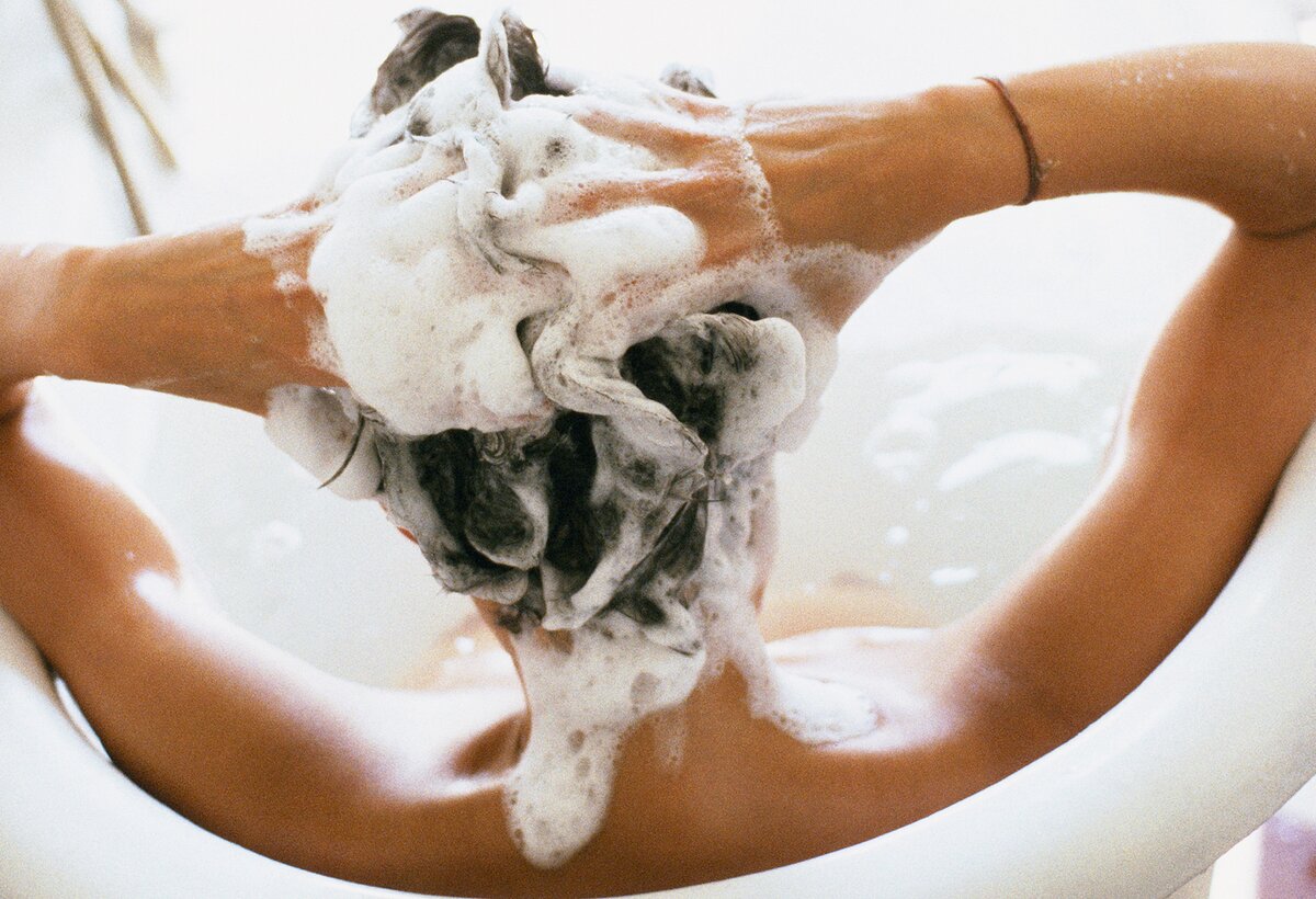 Luxurious hair wash in a serene bath%2C showcasing rich lather from a color-protecting shampoo%2C perfect for maintaining vibrant hues