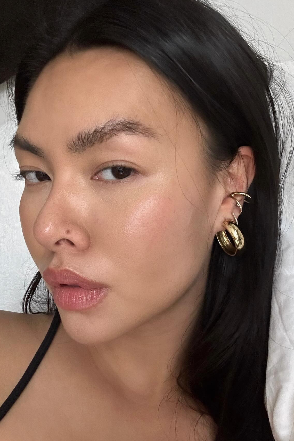 Close-up of a model showcasing a natural makeup look with glossy lips%2C styled black hair%2C and layered gold hoop earrings%2C highlighting an effortless beauty aesthetic