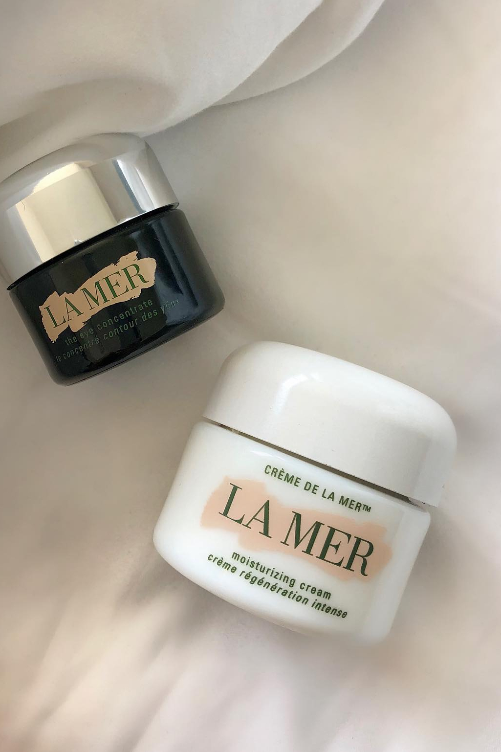 Cr%C3%A8me de la Mer moisturizing cream and eye concentrate displayed on a soft white backdrop%2C highlighting luxury skincare essentials