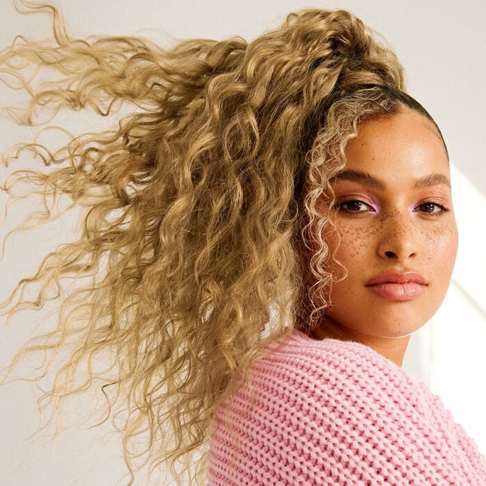 A woman in pink knitwear with hair extensions.