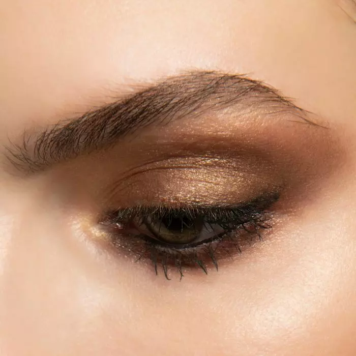 A woman's eye after applying metallic brown shimmer eye shadow.