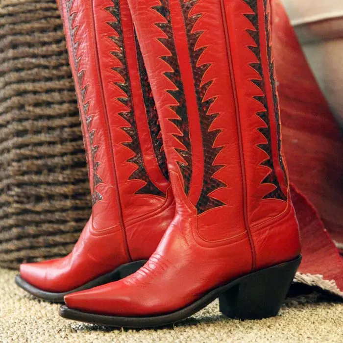 Red leather cowboy boots with black details and black heels. 