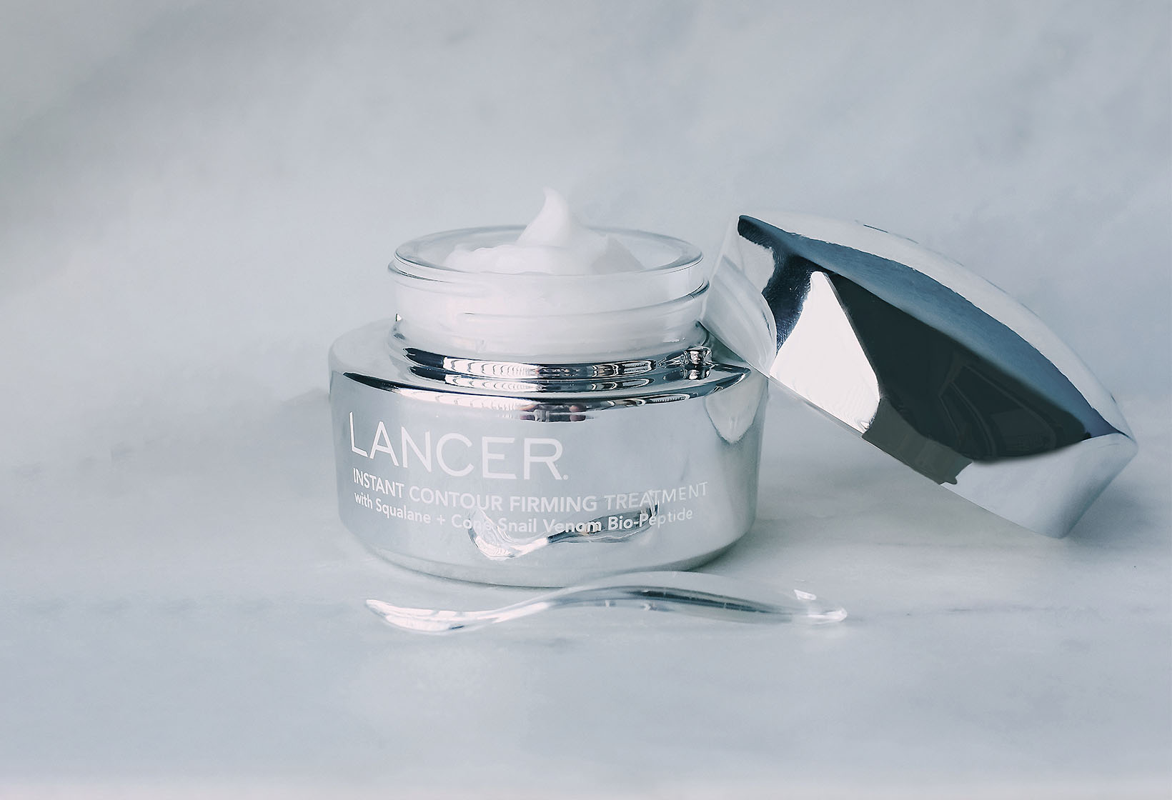 Lancer Instant Contour Firming Treatment jar reflecting a sleek silver design%2C featuring a smooth white cream inside%2C perfect for revitalizing skincare routines