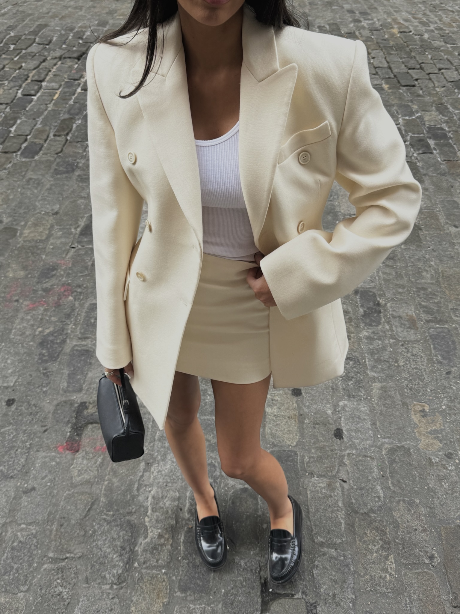 Cream double-breasted blazer styled with a fitted white tank top%2C paired with a beige mini skirt and black loafers%2C effortlessly chic for summer outings