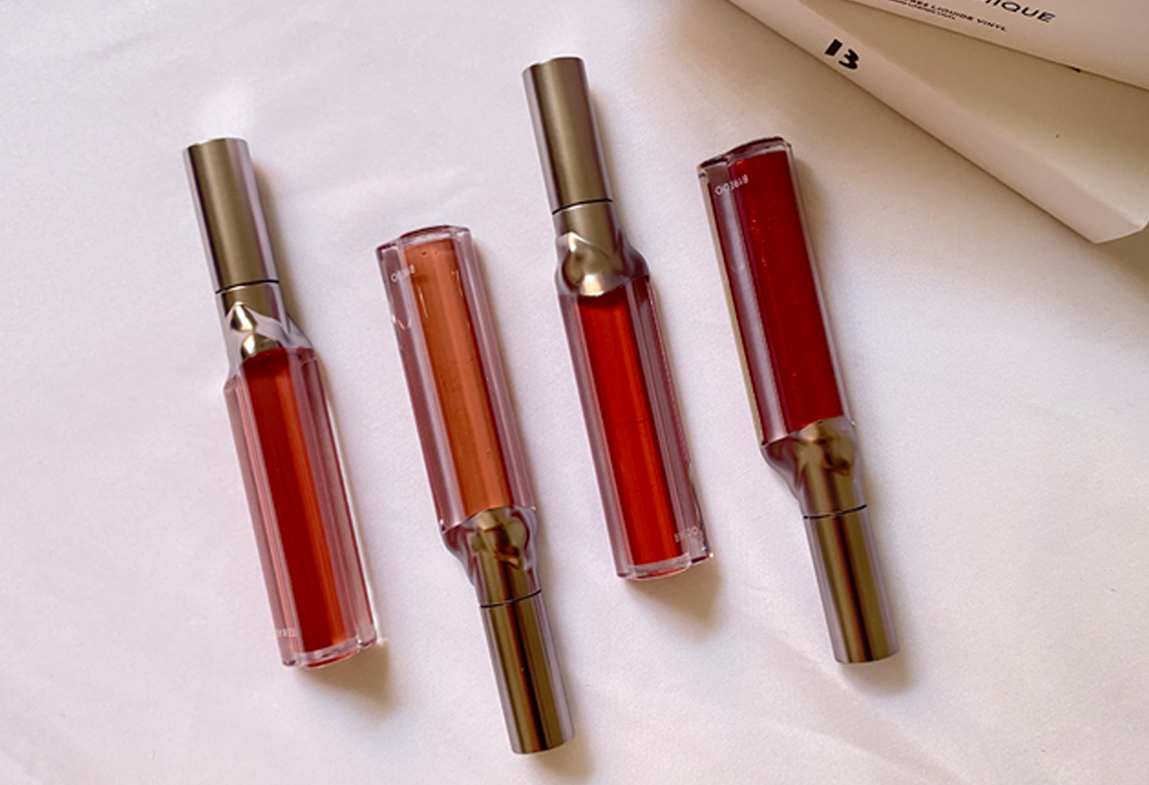 Byredo liquid lipstick vinyl collection showcasing four sleek%2C vibrant shades in transparent tubes with metallic caps on a light background