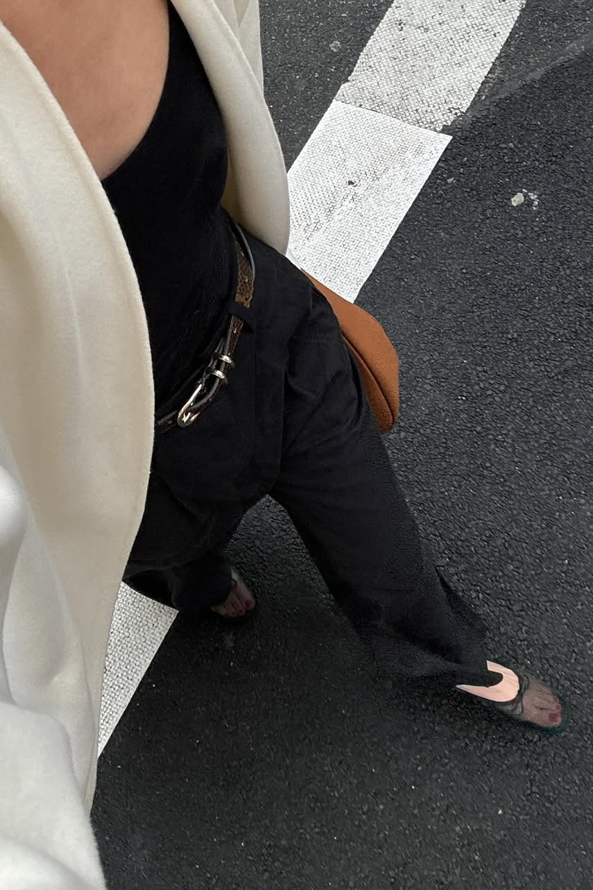 Overhead street style look with cream blazer%2C black tank and black jeans%2C brown leather shoulder bag at a city crosswalk