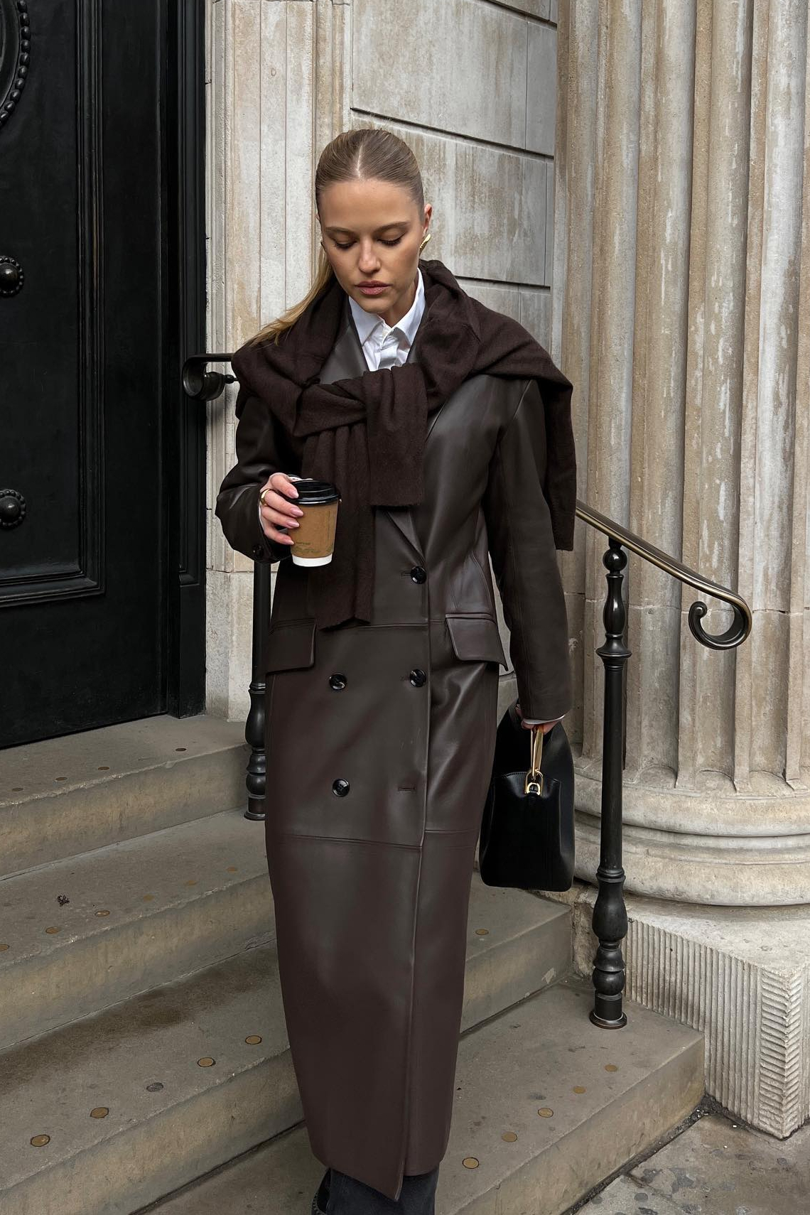Chic oversized brown leather trench coat layered over a white shirt%2C paired with a dark brown scarf and black handbag%2C perfect for fall styling