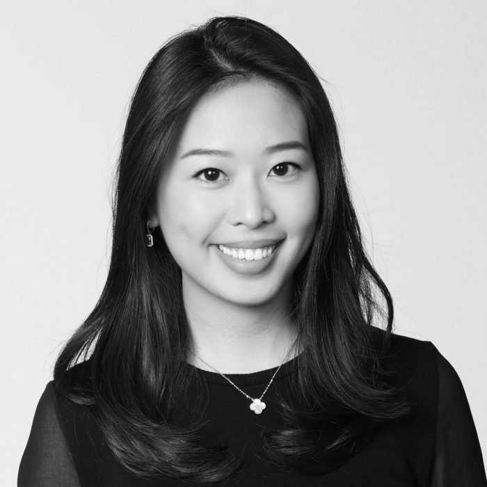 A woman with mid-length black hair smiles while wearing a black tee.