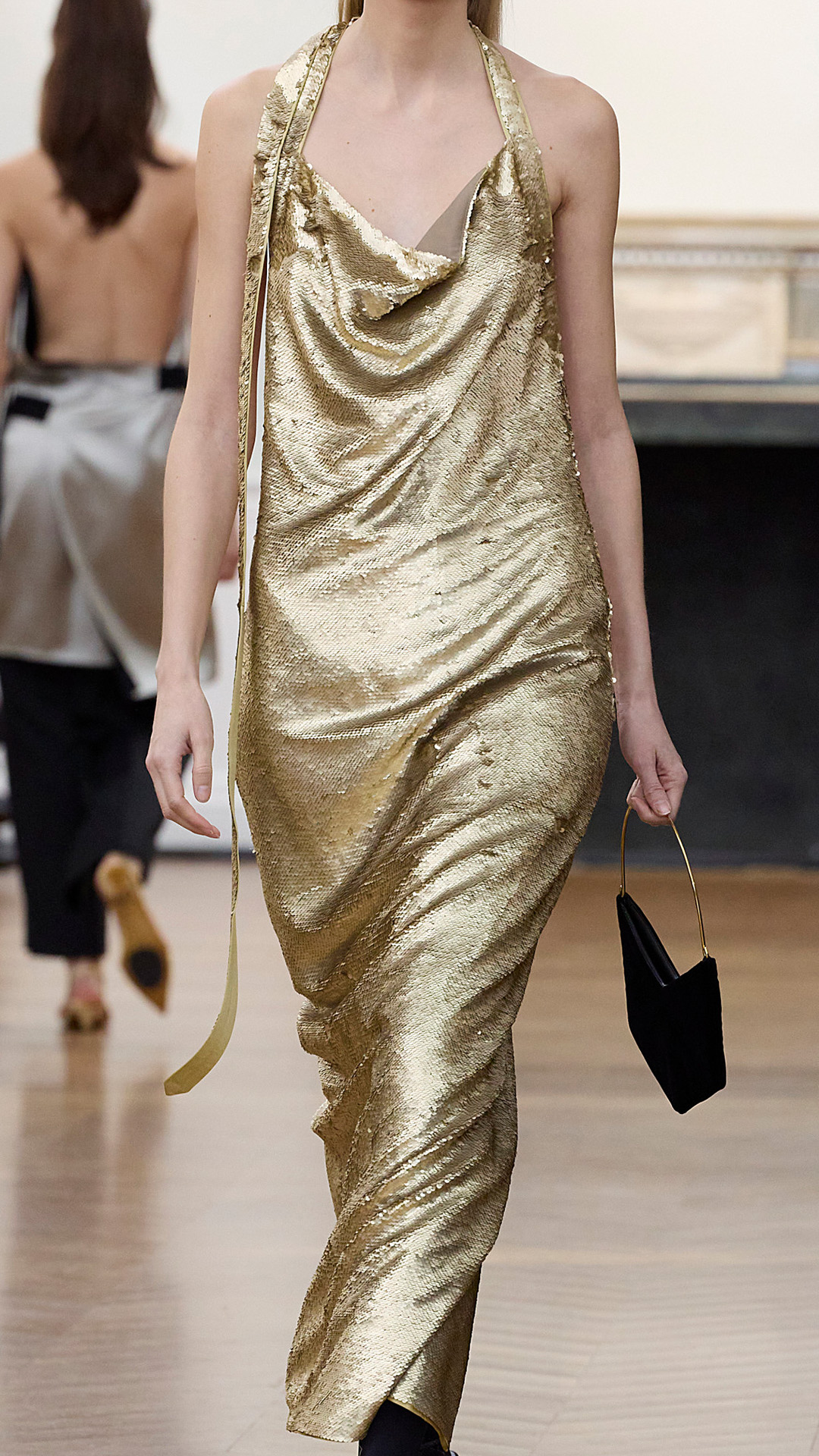 Sleek golden metallic dress from the latest holiday collection%2C featuring a draped silhouette and minimalistic black handbag for an elegant look