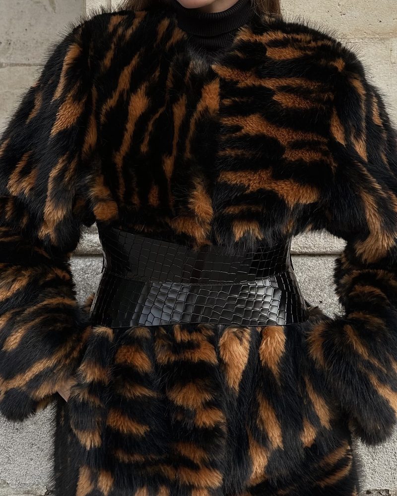 Bold statement coat featuring a striking black and orange tiger print%2C cinched at the waist with a glossy patent leather belt%2C perfect for the fall season
