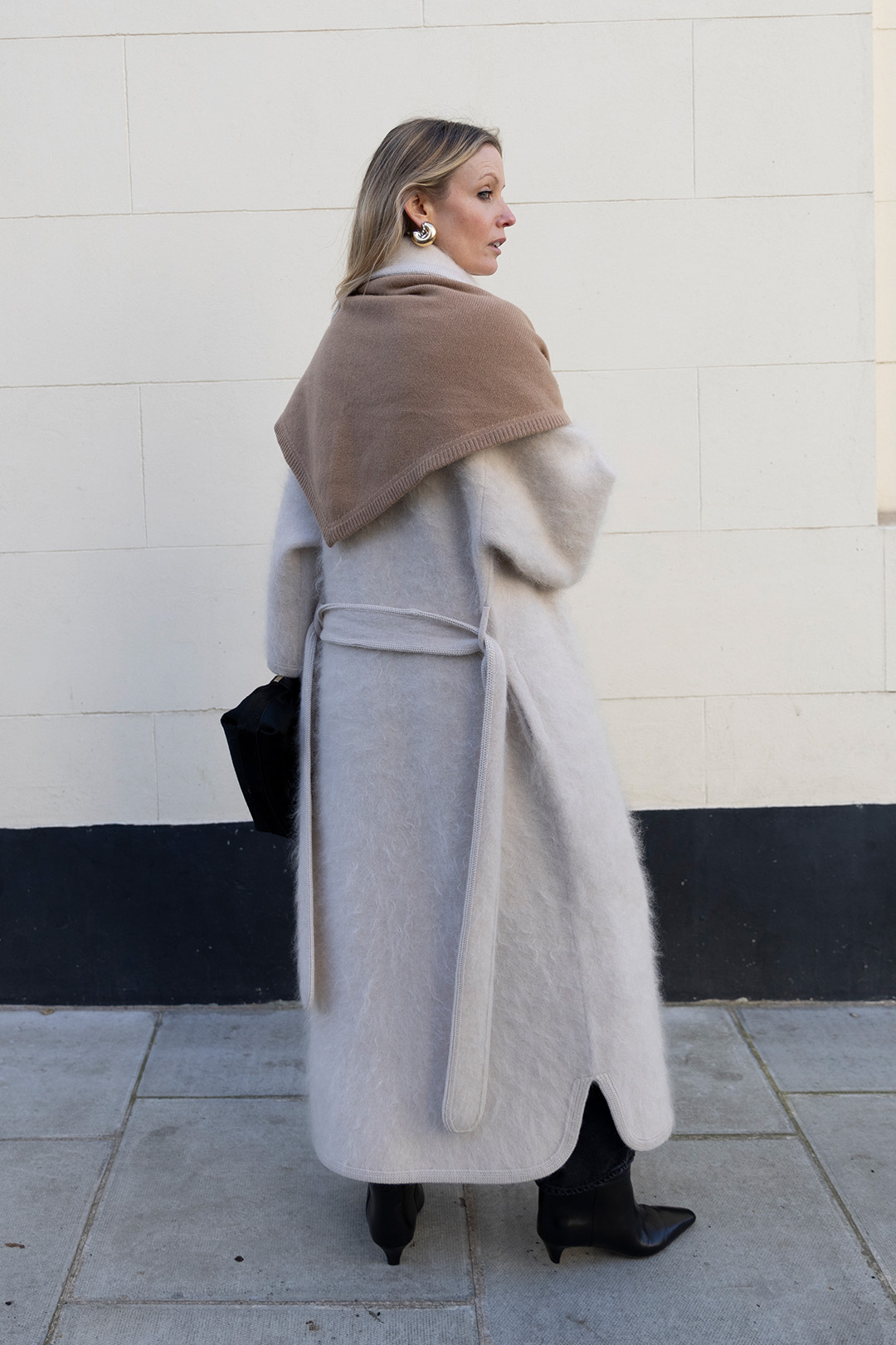 Cozy winter outfit featuring a soft gray oversized coat with a belted waist%2C paired with a contrasting brown knitted shawl and chic black ankle boots