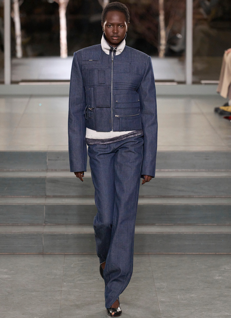 Model wearing structured Tory Burch dark denim zip-front jacket with matching trousers on modern runway
