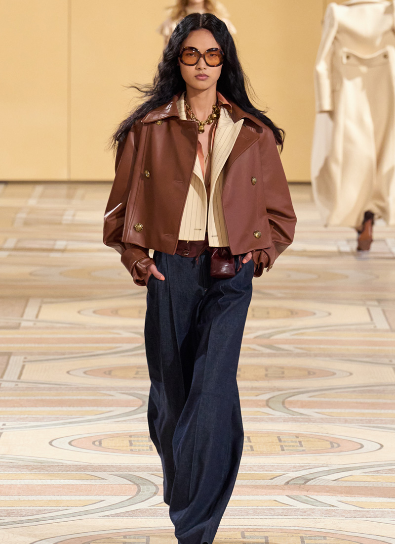 Model wearing Zimmermann brown leather cropped jacket with cream blouse and wide-leg jeans on runway