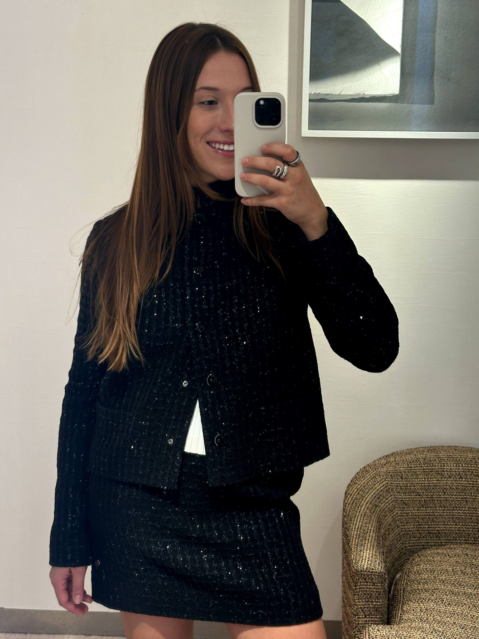 Chanel Cruise 2024%2F2025 features a chic black tweed ensemble with a fitted jacket and mini skirt%2C accented by subtle shimmer