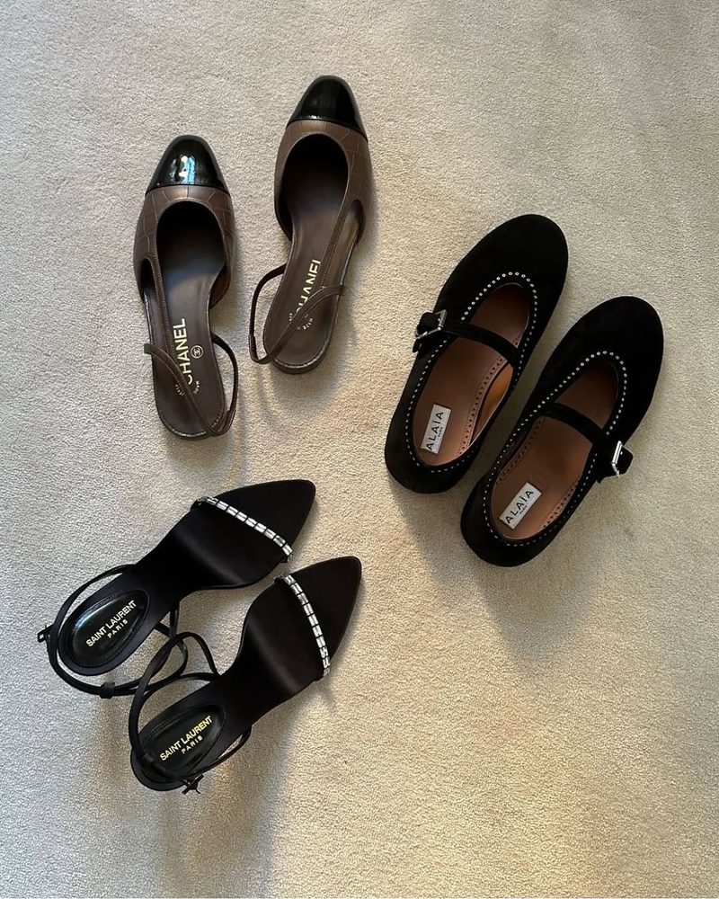 Chanel brown crocodile print heels with black patent toe cap%2C Saint Laurent black satin heels featuring an elegant crystal strap%2C and Ala%C3%AFa black kitten heels with studded details on a plush beige surface.