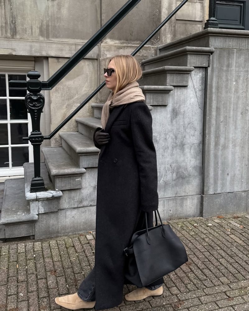 Elegant black coat from The Frankie Shop%2C paired with relaxed jeans from Arket%2C beige boots%2C and a chic black bag from The Row%2C perfect for cold weather outings