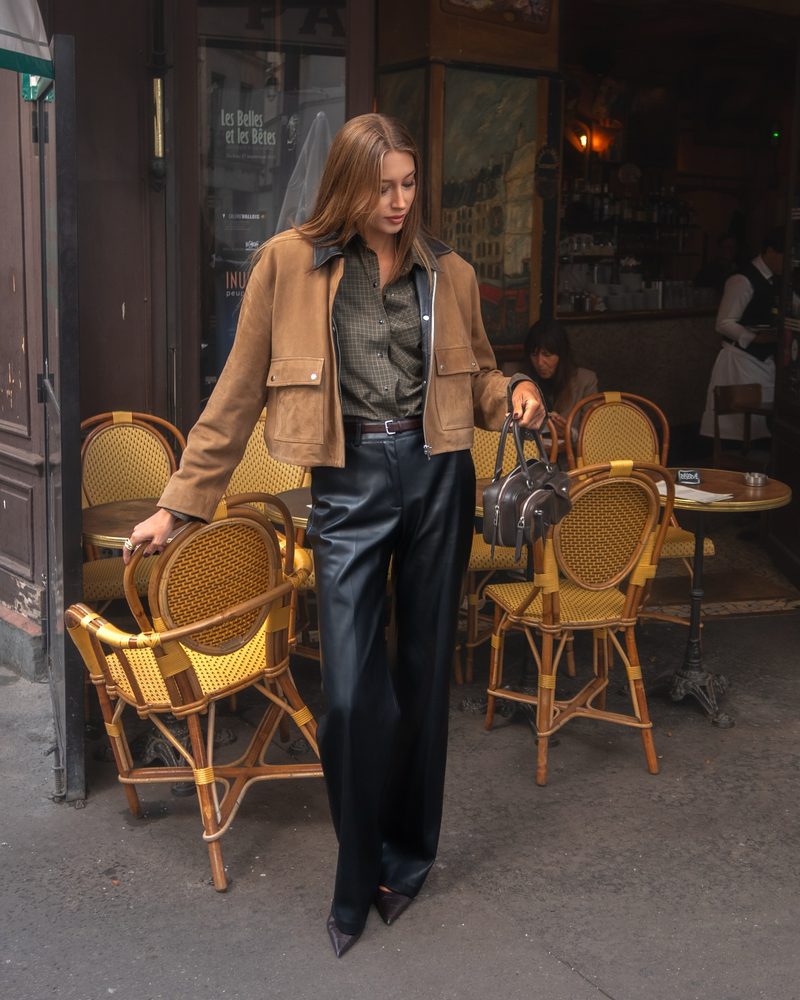Chic autumn outfit featuring high-waisted black leather pants%2C a brown suede jacket%2C and a plaid shirt%2C paired with elegant heels and a stylish handbag