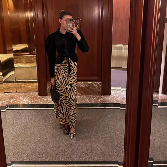 Stylish outfit featuring a black velvet blouse with puff sleeves, a tiger-striped skirt, and chic animal-print heels, complemented by a small black bag.