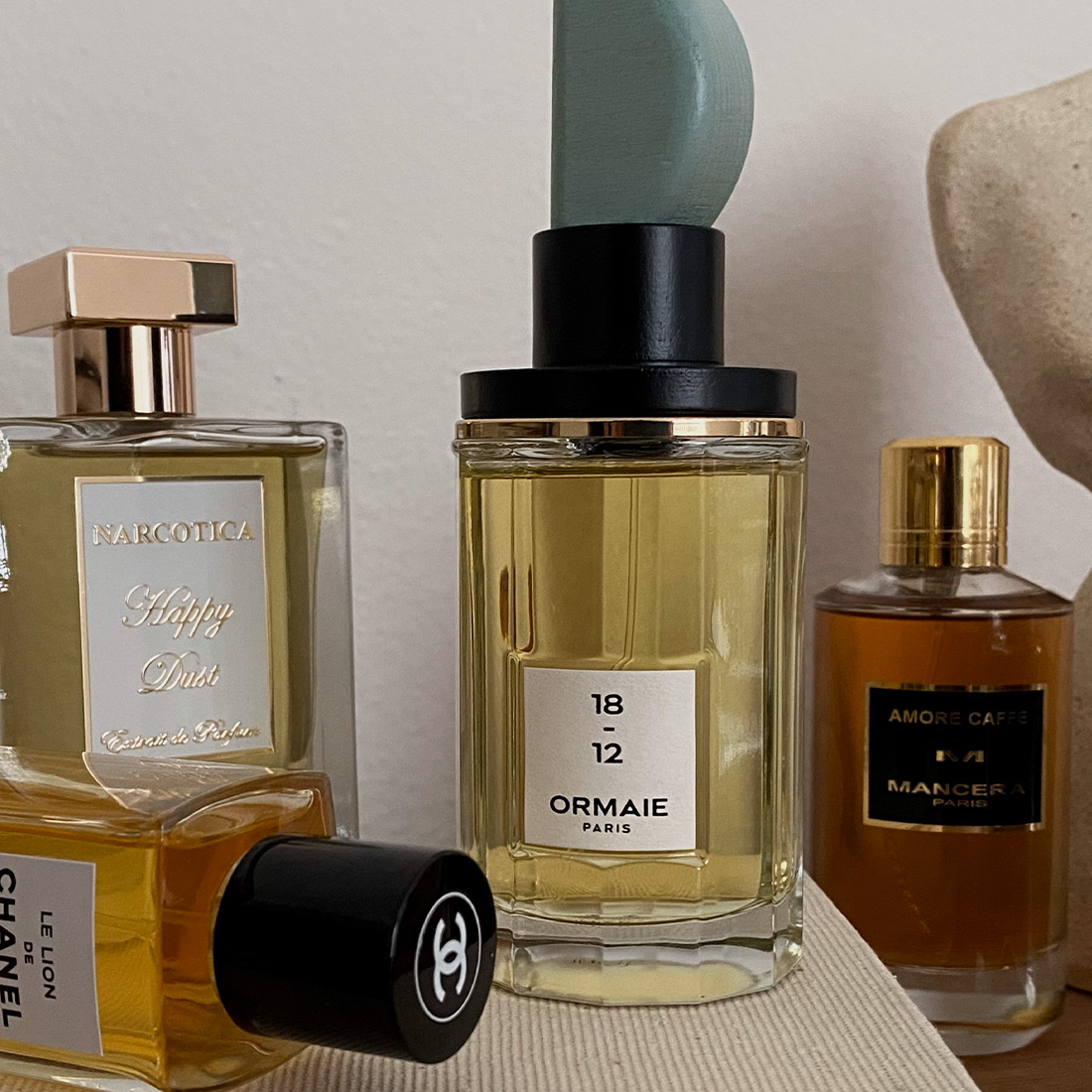 Chanel and Ormaie Paris fragrances displayed elegantly%2C featuring Narcotica%27s Happy Dust%2C an amber glass bottle%2C and the stylish 18-12 bottle
