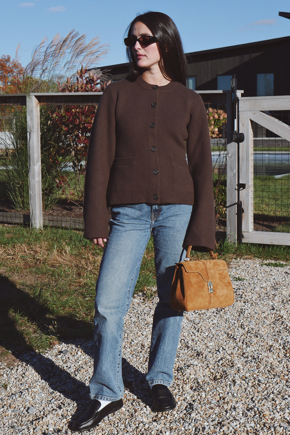 Chic brown knit cardigan paired with light-wash flared jeans and a tan suede handbag%2C styled with sleek black loafers and sunglasses