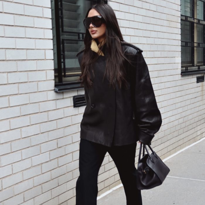 A woman wearing a black leather Khaite jacket and The Row's Margaux bag.