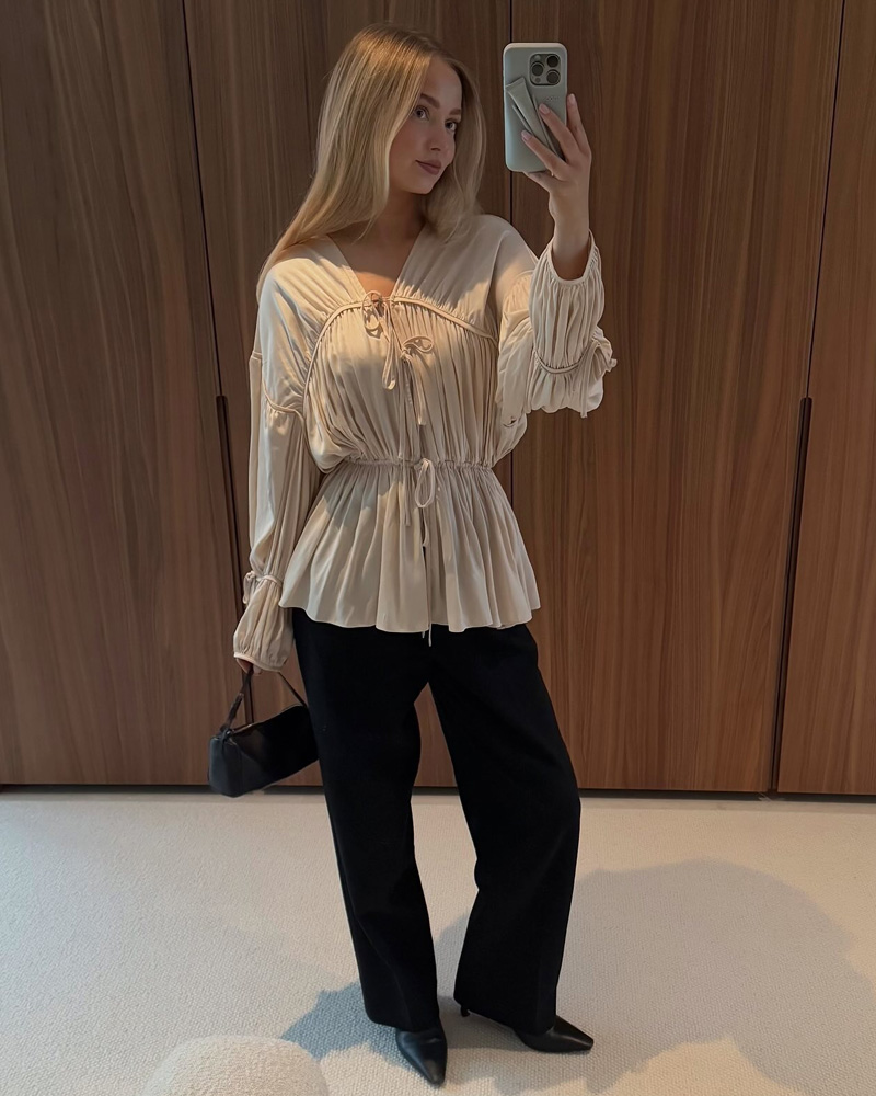 Mirror selfie in cream boho peplum blouse%2C black wide-leg trousers and mini shoulder bag indoors