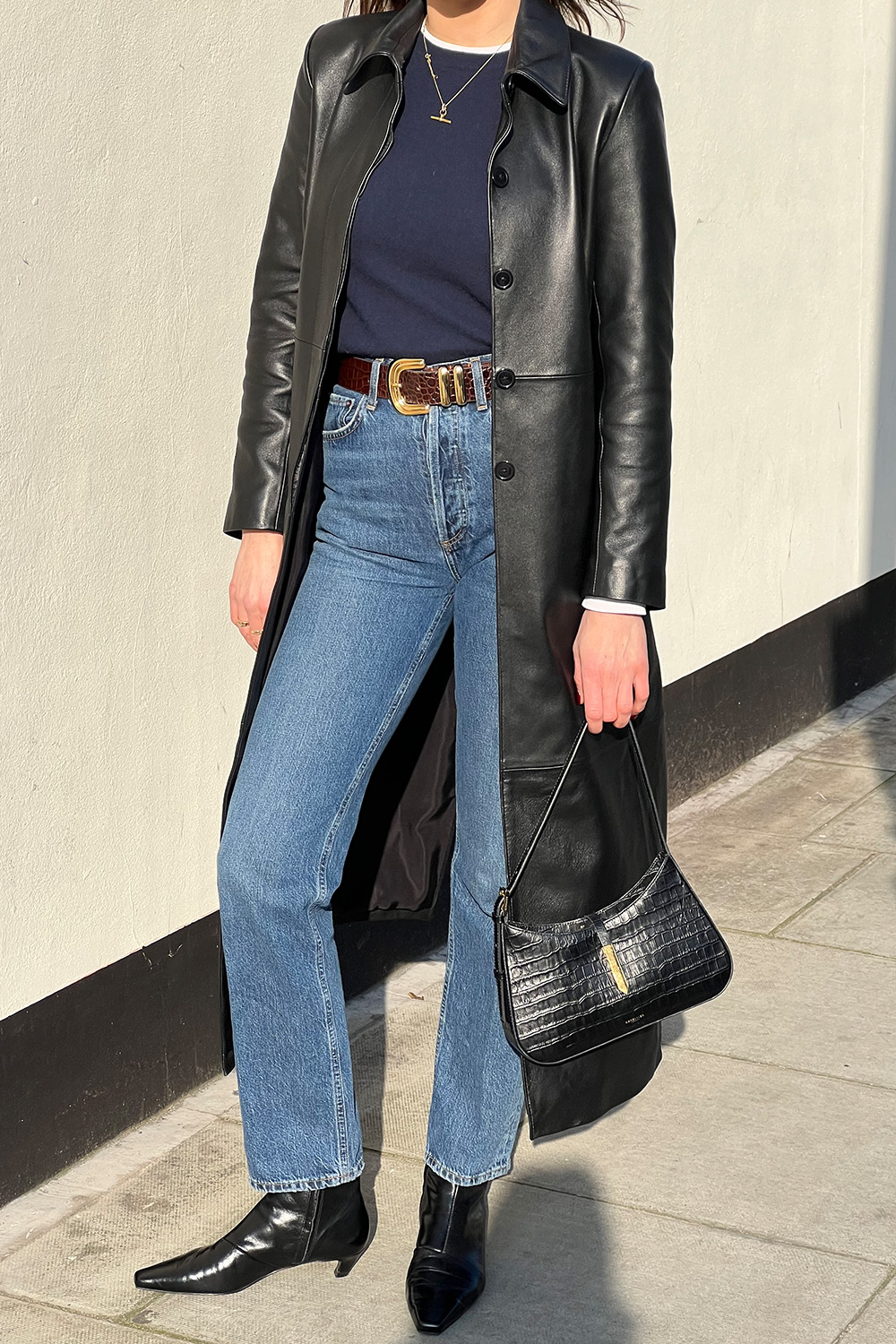 Nour Hammour black leather coat styled with blue high-waisted jeans and black ankle boots%2C complemented by a chic crocodile-embossed handbag