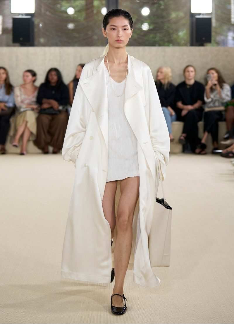 White oversized trench coat over a mini slip dress with pearls and tote bag on the runway