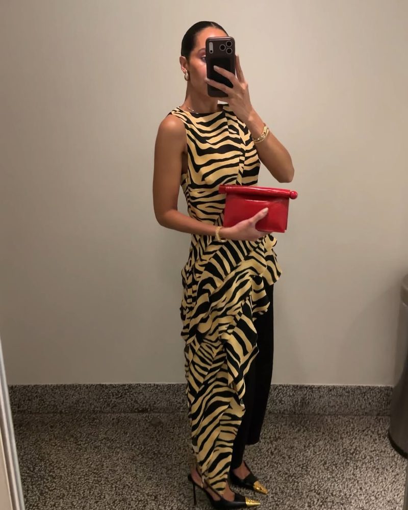 Zebra print dress styled with black heels and a red clutch for a bold animal print evening look
