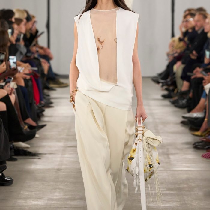 Elegant Sportmax ensemble featuring a flowing white top with sheer detailing and wide cream trousers, complemented by a stylish bag adorned with floral accents