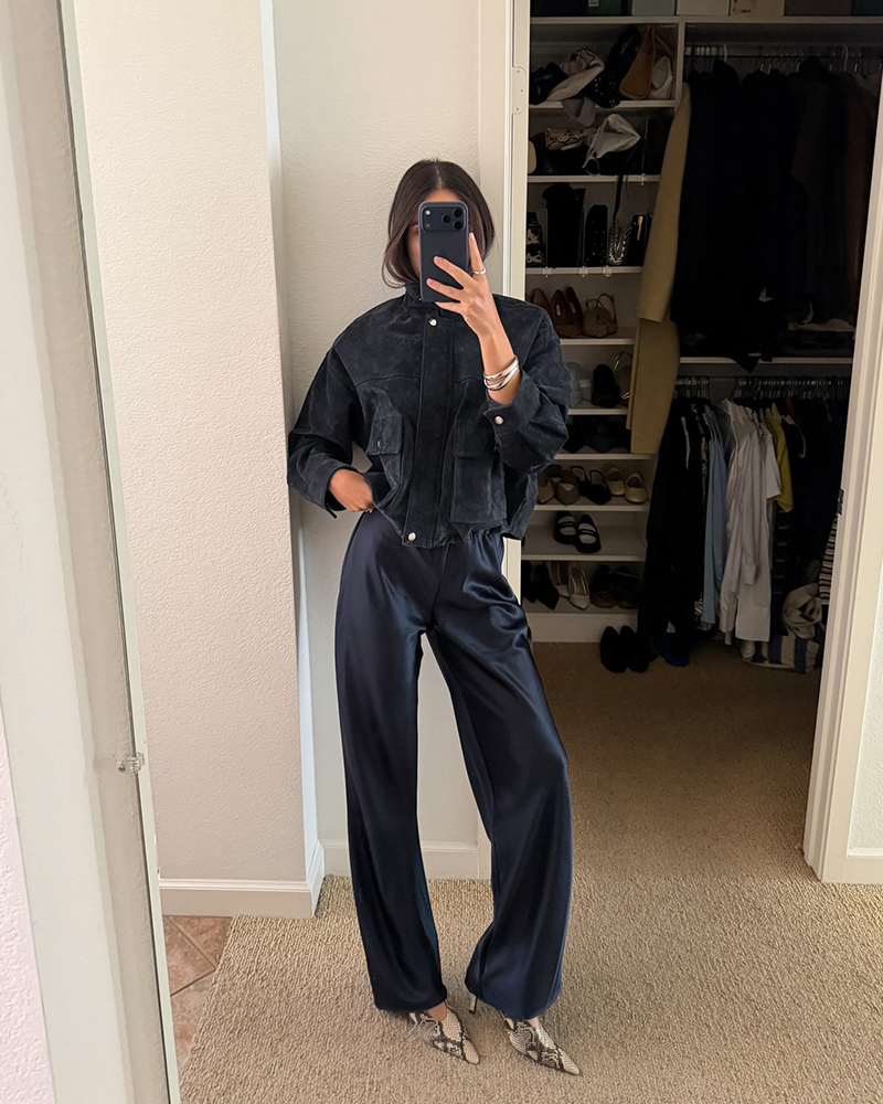 Mirror selfie outfit featuring cropped black suede jacket%2C navy satin wide-leg trousers and snakeskin pointed heels in a walk-in closet setting