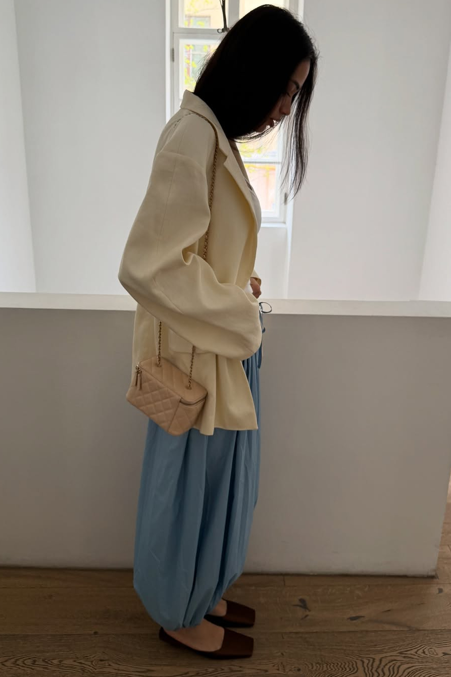Light beige oversized blazer paired with a flowing light blue skirt%2C complemented by a quilted beige handbag and brown flats