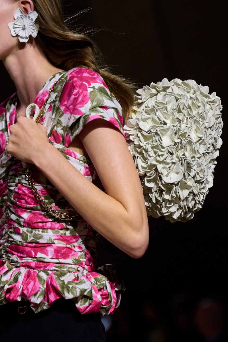 White floral heart-shaped handbag with layered petal appliqués, paired with a pink rose print top for a romantic runway look