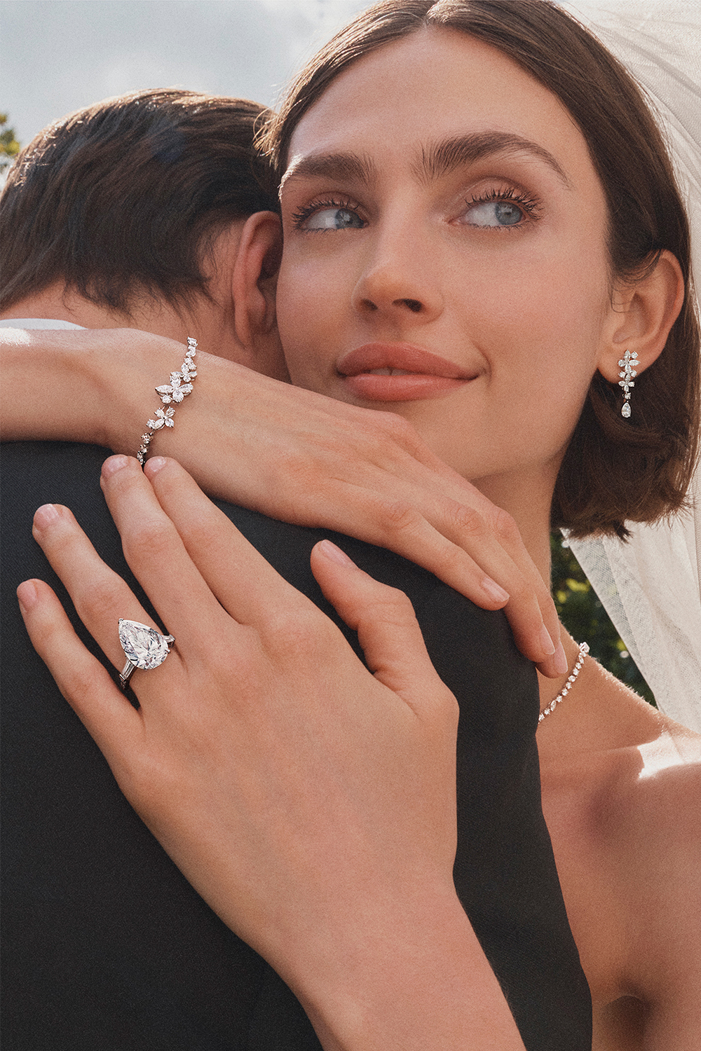 Elegant Graff diamond jewelry showcasing a pear-shaped engagement ring%2C delicate drop earrings%2C and a floral bracelet%2C perfect for a wedding day