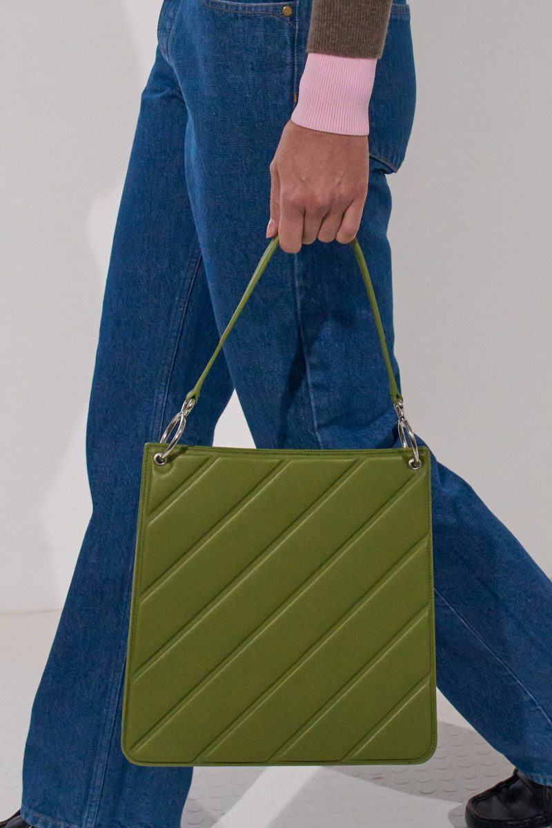 Olive green leather shoulder bag with diagonal quilting, styled with blue denim jeans for a modern casual look