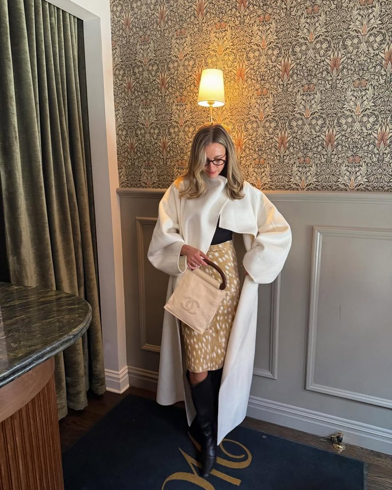 Chanel handbag paired with a polka-dot midi skirt and an oversized white coat%2C capturing effortless spring fashion style in an elegant setting
