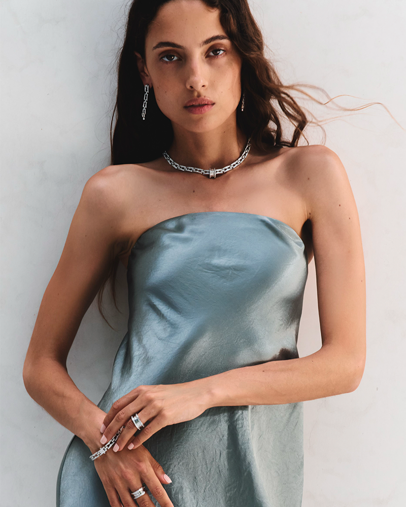 Sleek satin strapless dress in soft teal%2C paired with Bvlgari silver jewelry%2C including layered necklaces and stacking rings