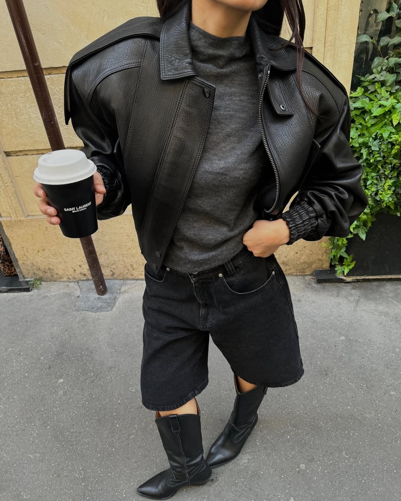 Chic black Bermuda shorts paired with a dark gray turtleneck and a stylish leather jacket%2C complemented by knee-high black boots