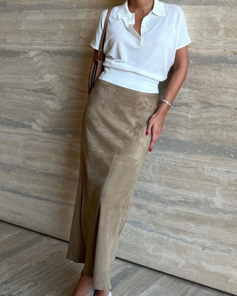 Chic summer outfit featuring a white polo top paired with a tan suede midi skirt%2C complemented by sleek heeled sandals and a stylish bag