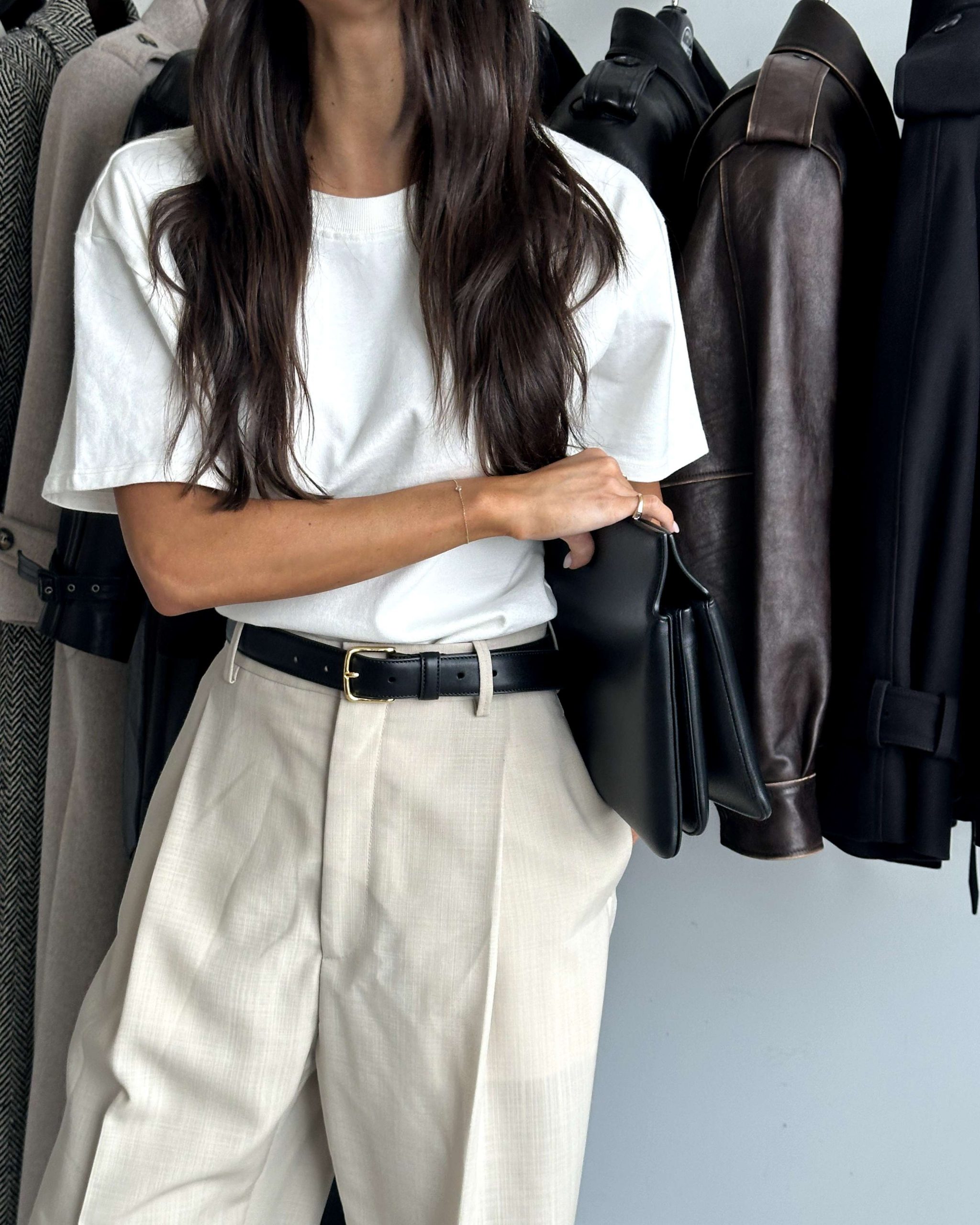 Minimal outfit with a white crewneck T-shirt%2C beige pleated trousers%2C black leather belt%2C and sleek shoulder bag for chic everyday style