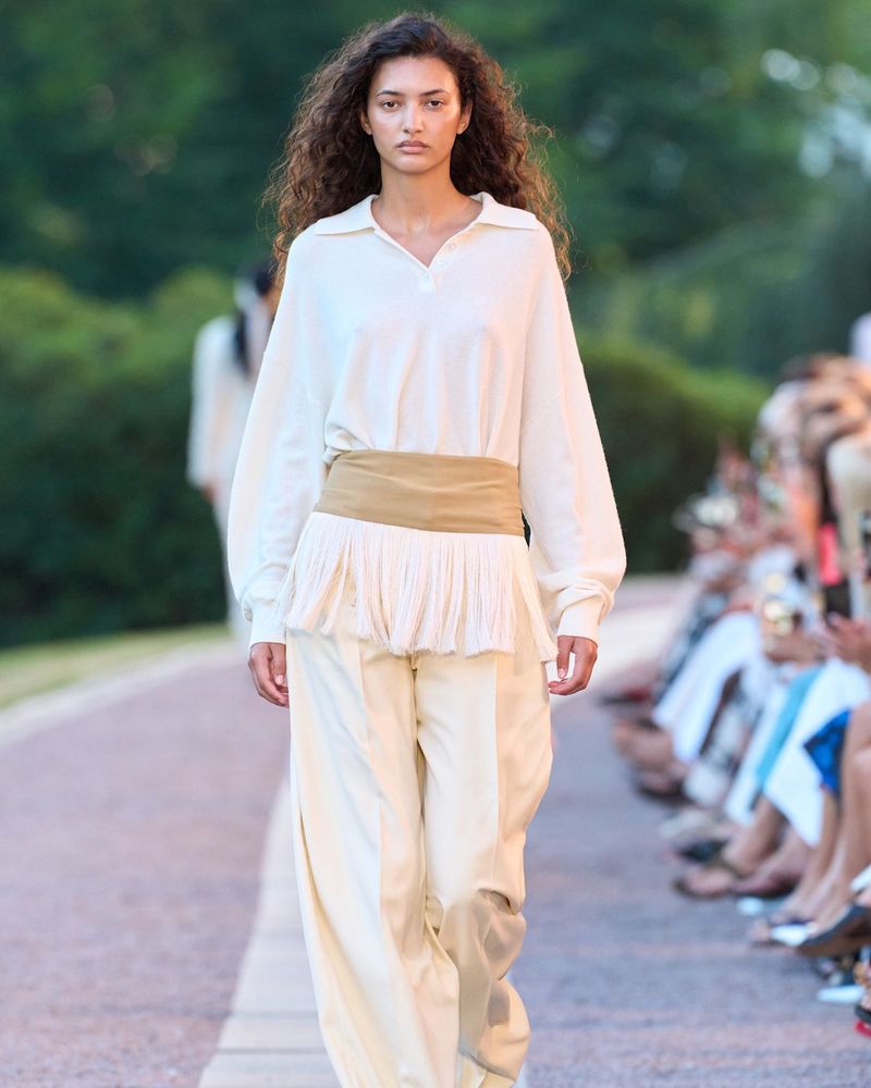 Malene Birger spring outfit featuring a cream long-sleeve polo shirt%2C wide-leg beige trousers%2C and a fringed beige waist belt
