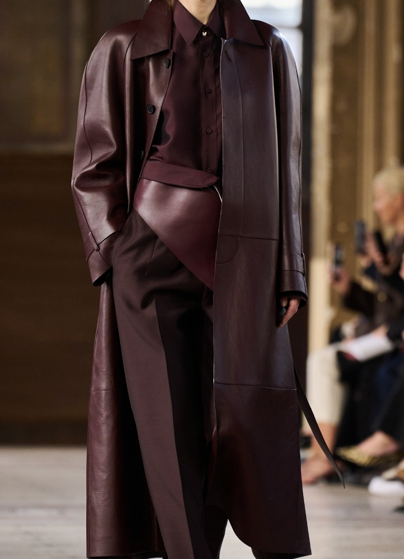 Burgundy leather long coat layered over a tonal shirt and tailored trousers on the runway
