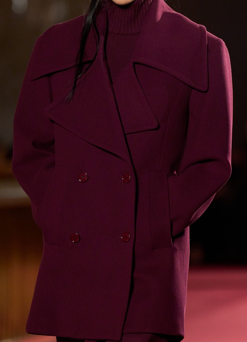 Deep burgundy double-breasted wool coat with sculptural lapels layered over a matching turtleneck on the runway