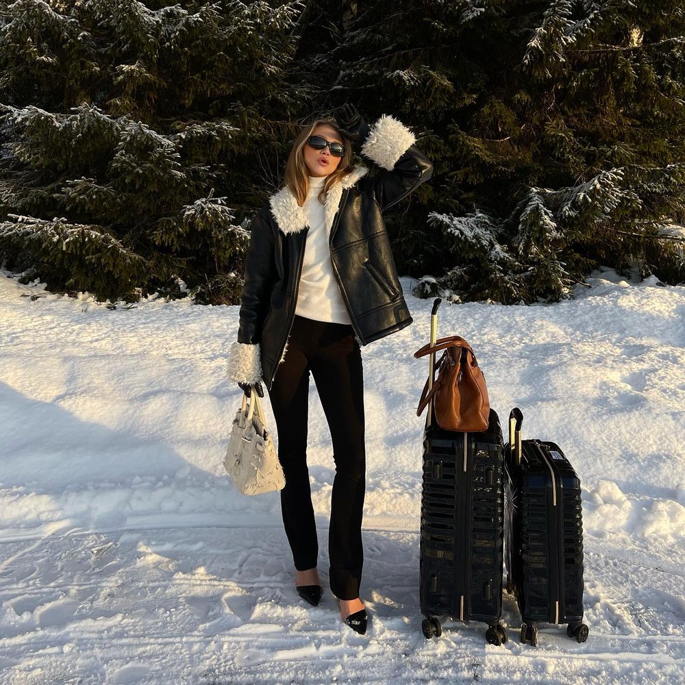 Chic winter outfit featuring a black leather jacket with white faux fur trim, paired with sleek black trousers and stylish high heels.