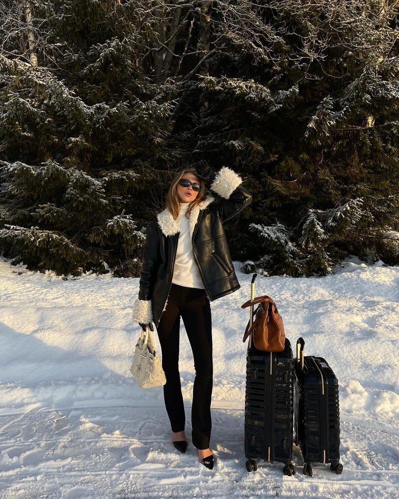 Chic winter outfit featuring a black leather jacket with white faux fur trim%2C paired with sleek black trousers and stylish high heels