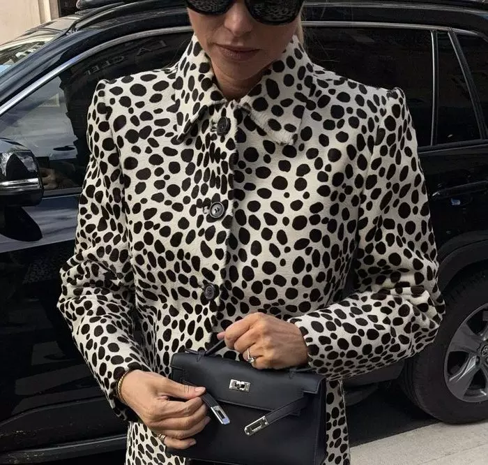 Polka dot print coat featuring a classic button-up design, paired with tailored black pants and sleek black flats for a chic look.