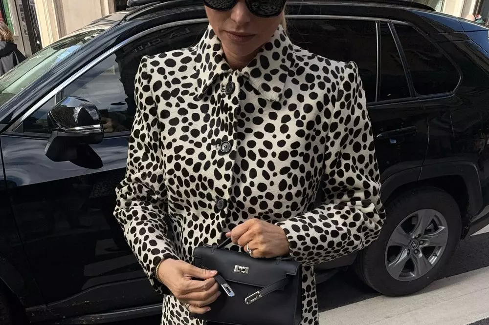 Polka dot print coat featuring a classic button-up design, paired with tailored black pants and sleek black flats for a chic look.